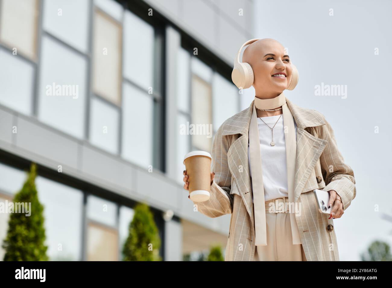 A young bald woman in elegant attire sips coffee while enjoying the ...