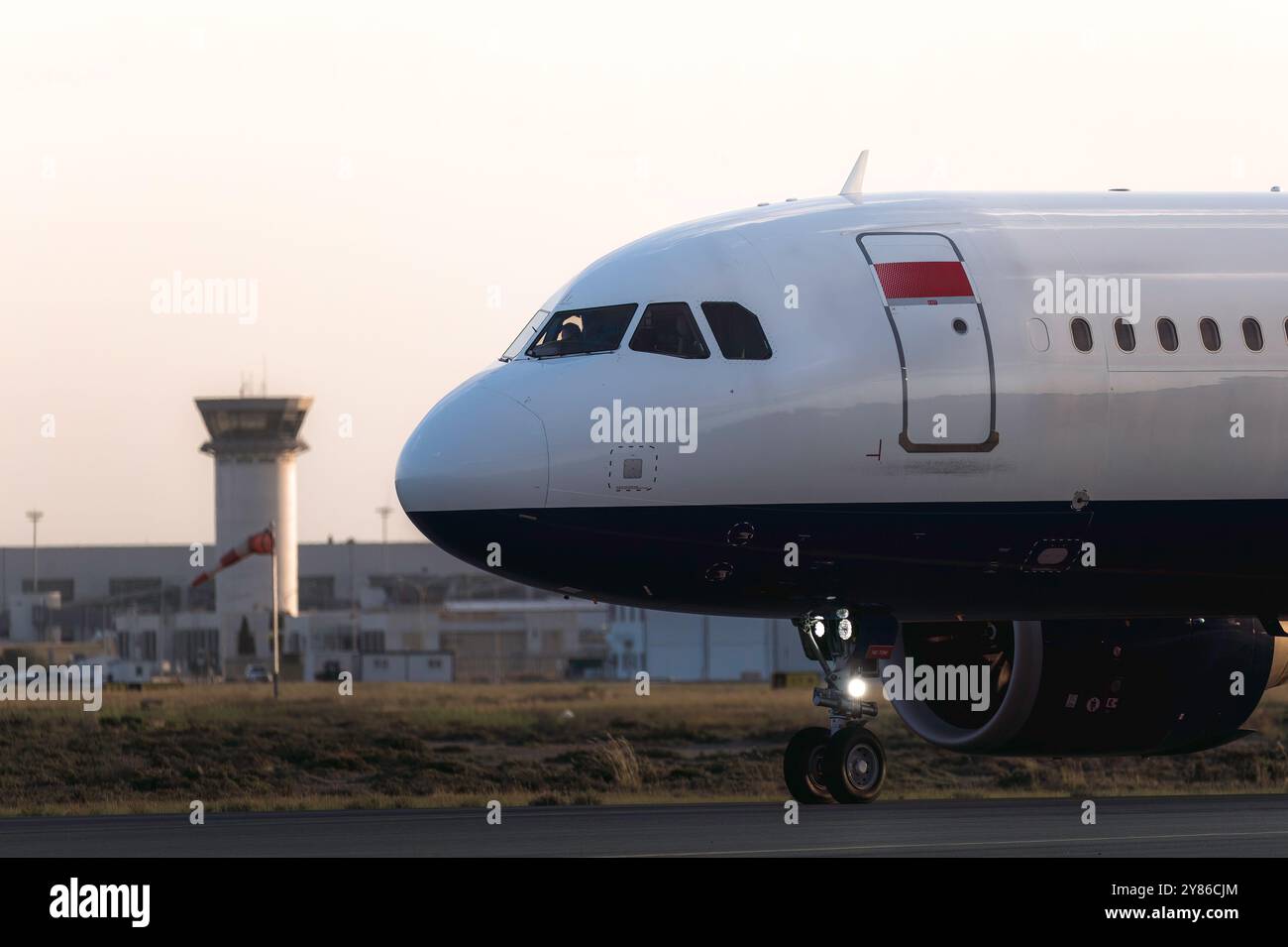 Airplane is taxiing on the runway at sunset with the pilots visible in the cockpit Stock Photo ...