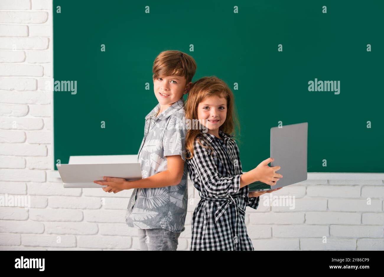 Portrait of children boy and girl with laptop computer and book at ...