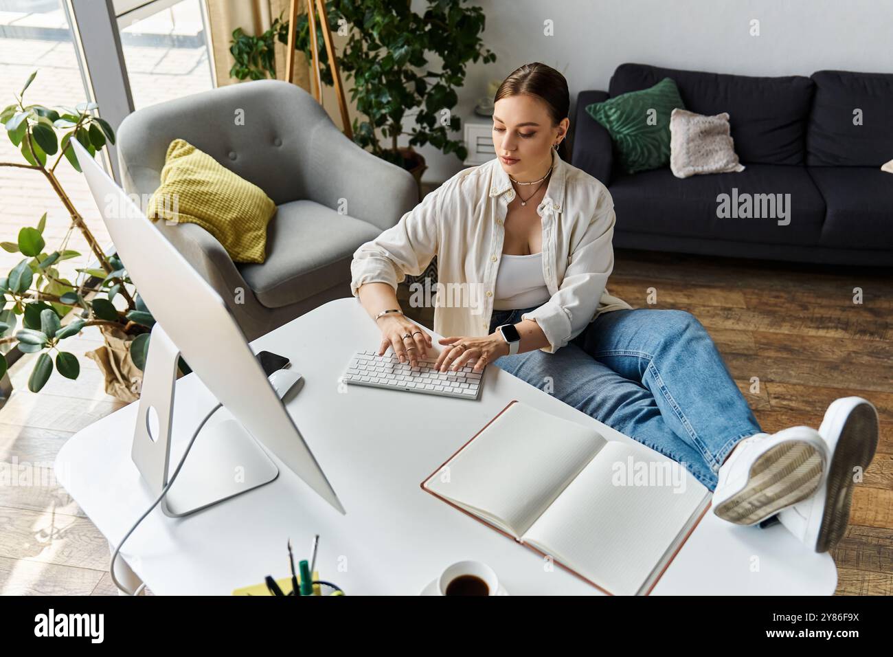 A young woman casually types on a keyboard while lounging in her ...