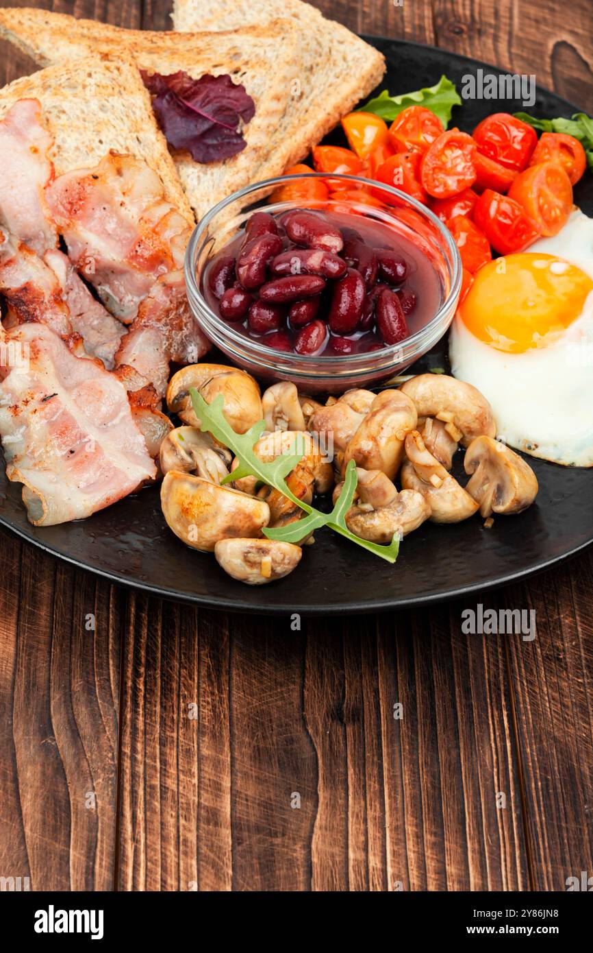 Fried bacon and eggs, toast and beans and vegetables. Traditional ...