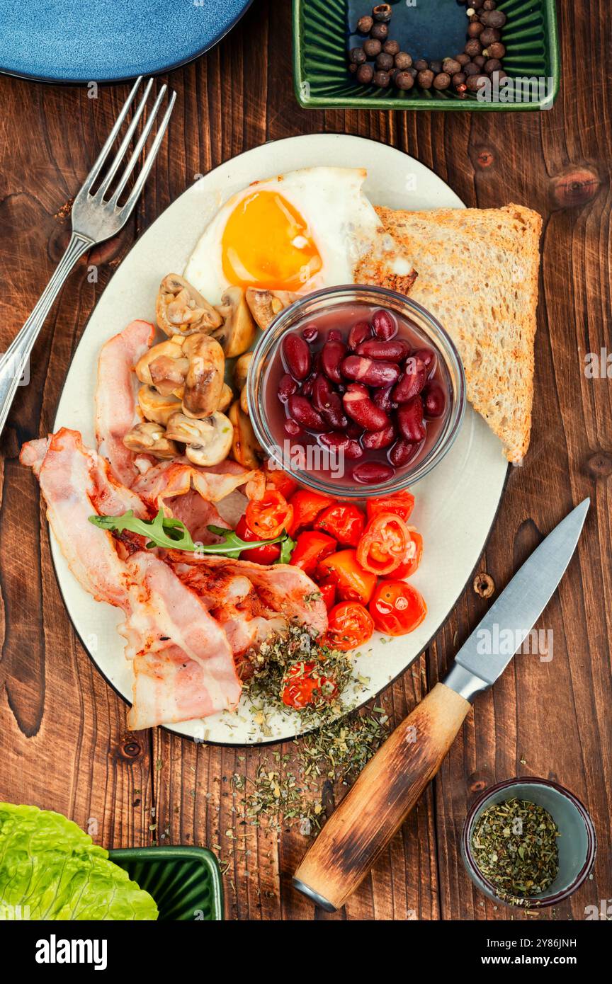 Fried bacon and eggs, toast and beans and vegetables. Traditional ...