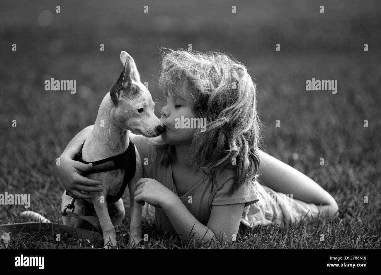 Smiling owner child lying lawn with pet doggy. Happy kid playing with ...