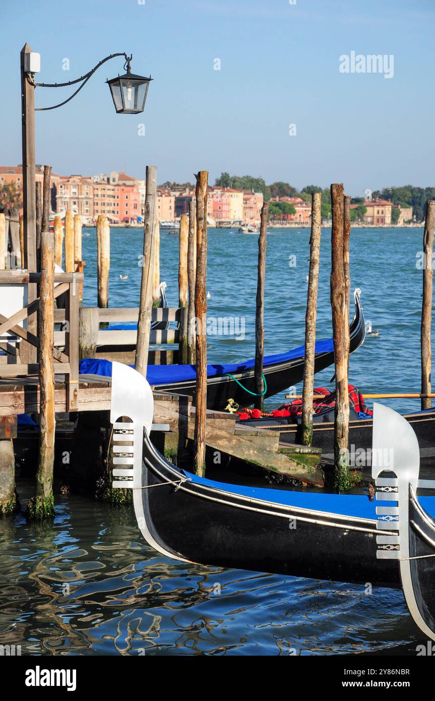 Gondolas swaying in Venice canals with historic buildings and blue sky ...