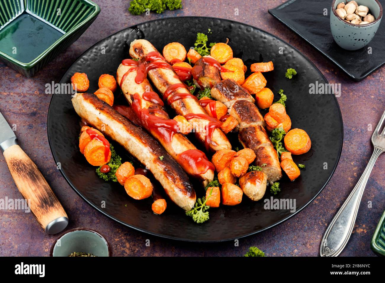 Baked or grilled turkey sausages with roasted carrots on the plate ...