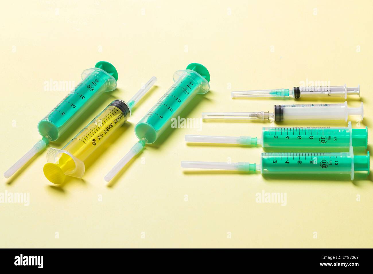 Top view of medical syringes with needles at yellow background with ...