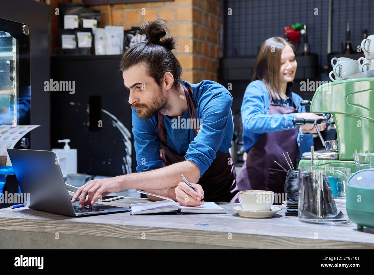 Two cafe workers working together behind counter, at coffee shop Stock ...