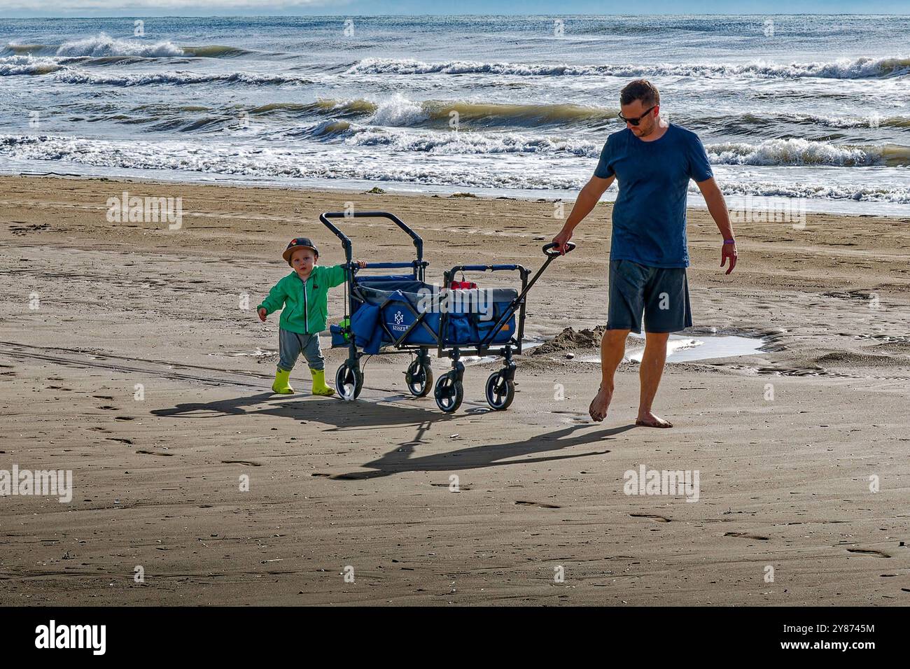 Gemeinsam. Vater und Sohn ziehen ihren Bollerwagen am Strand Cavallino ...