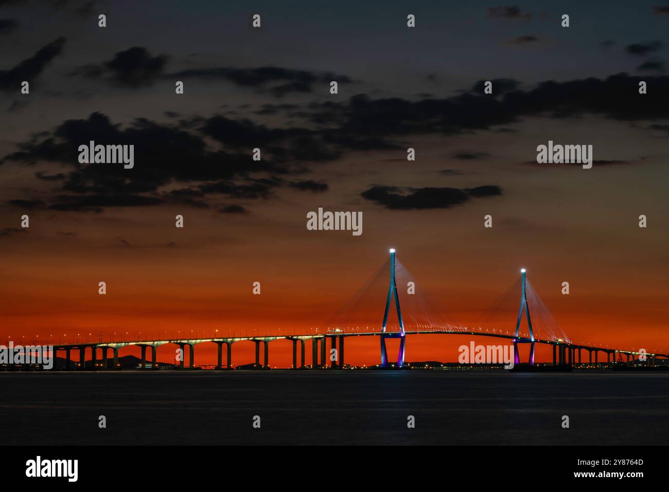 A dusk view of Incheon Bridge, illuminated with blue lights reflecting ...