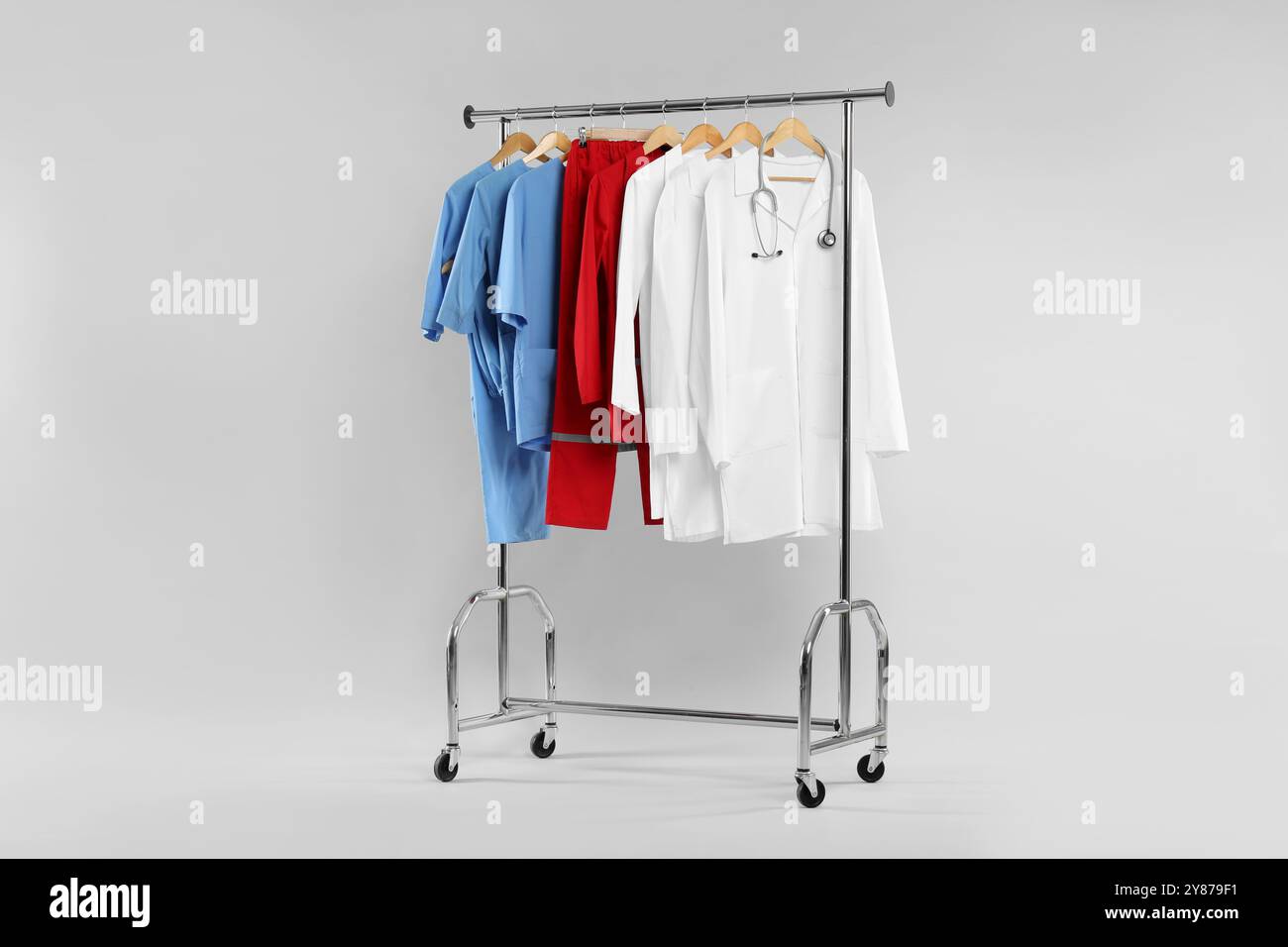 Different medical workers' uniforms and stethoscope on clothing rack ...