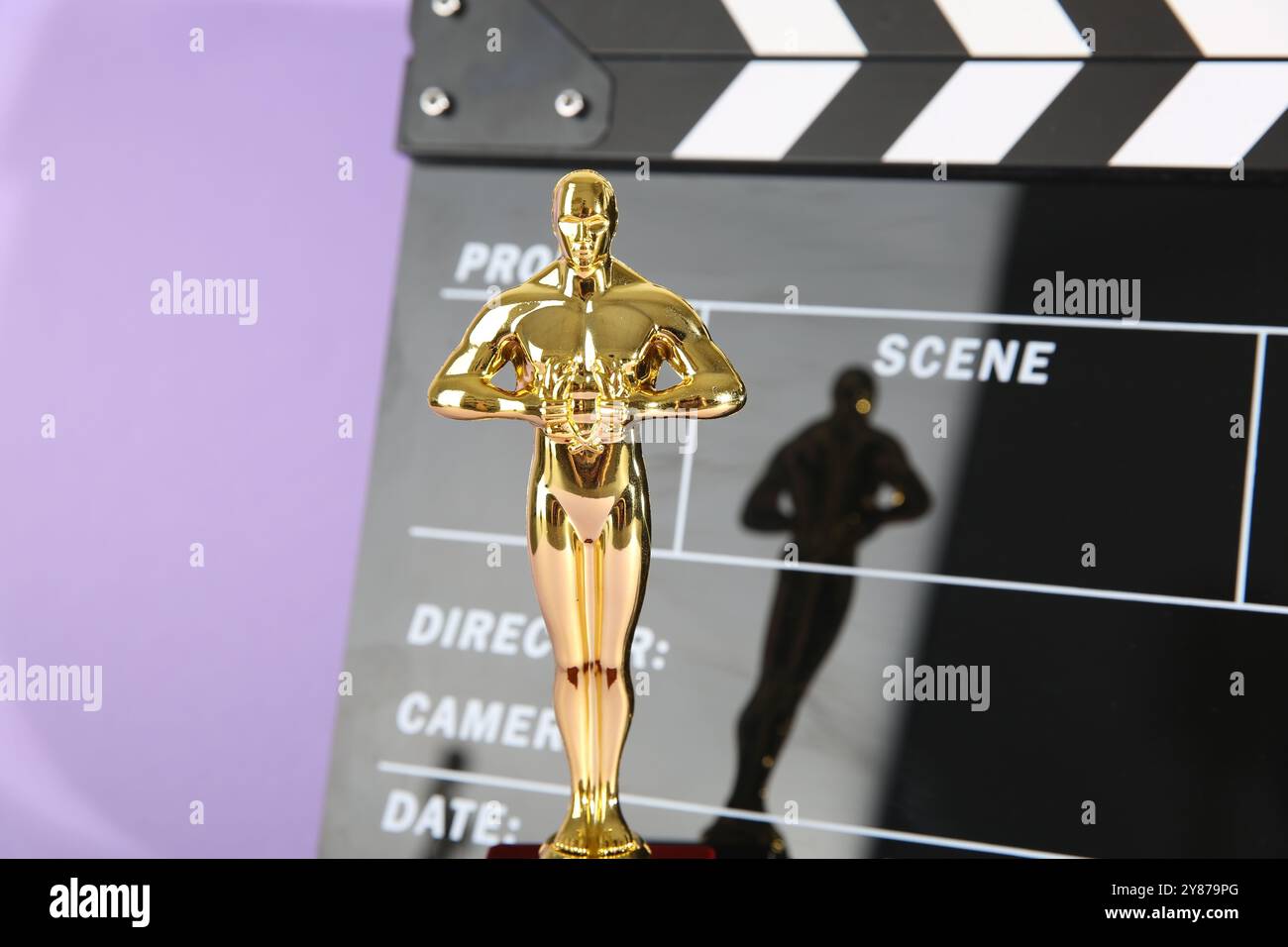 Golden Oscar award and movie clapper on violet background Stock Photo ...