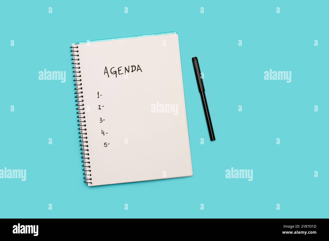 Agenda word handwritten in a white page of a notepad with a black ...