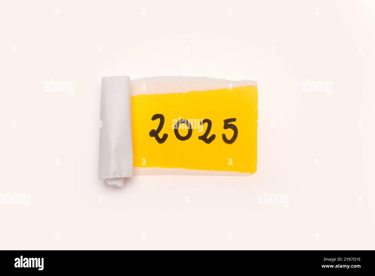 2025 handwritten on a yellow paper behind a white torn paper with copy ...
