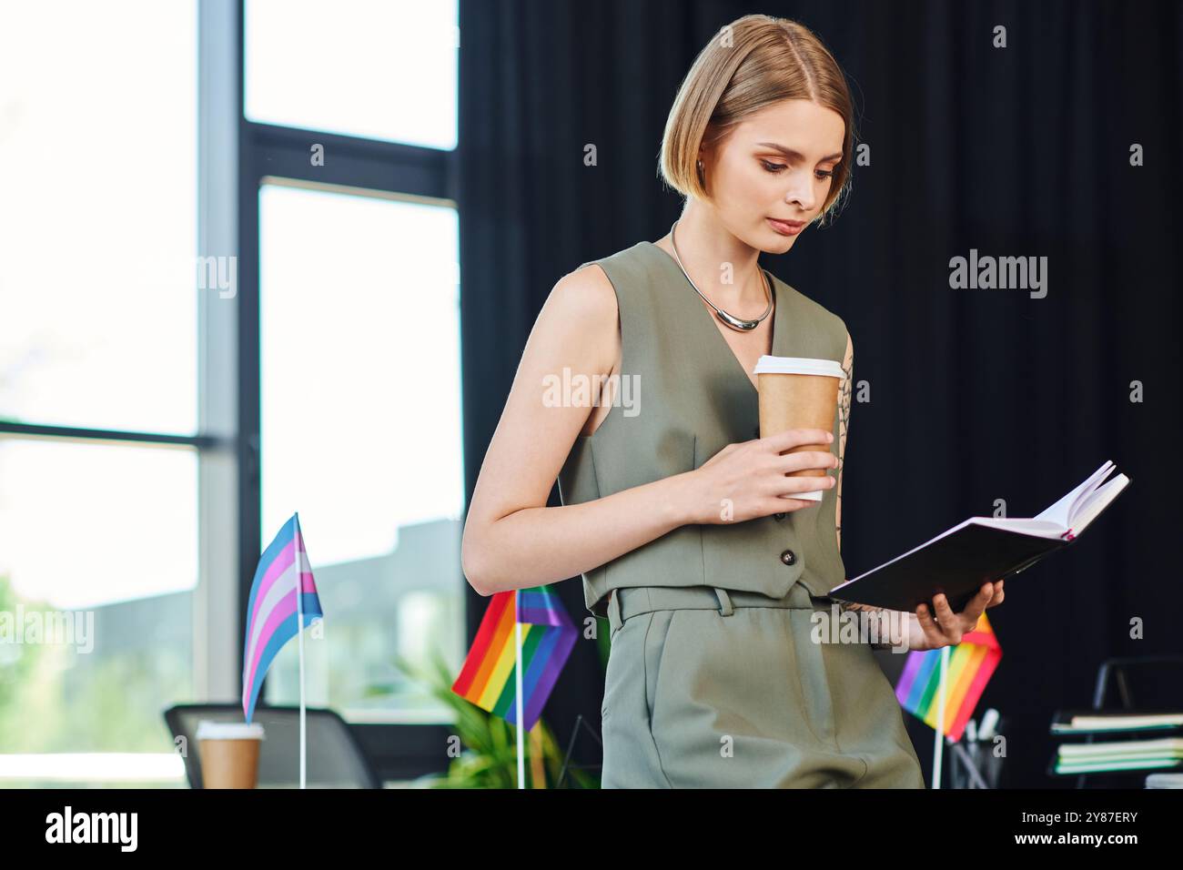 A thoughtful woman reviews notes in a lively office adorned with pride ...