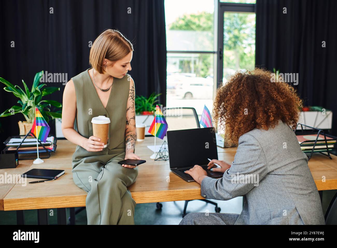 Two colleagues engage in a discussion while embracing a colorful ...