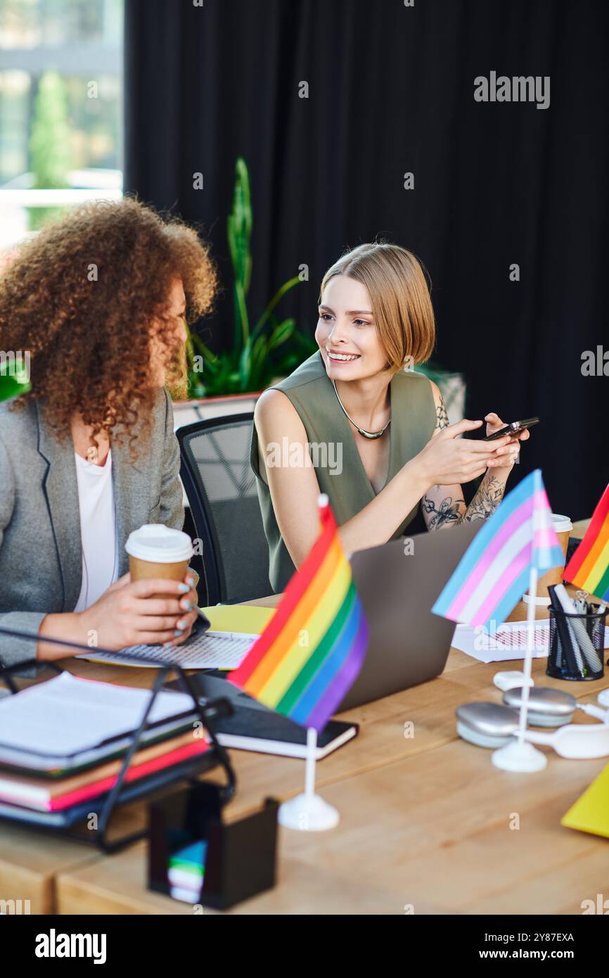 Two coworkers chat enthusiastically, proudly displaying pride flags in ...