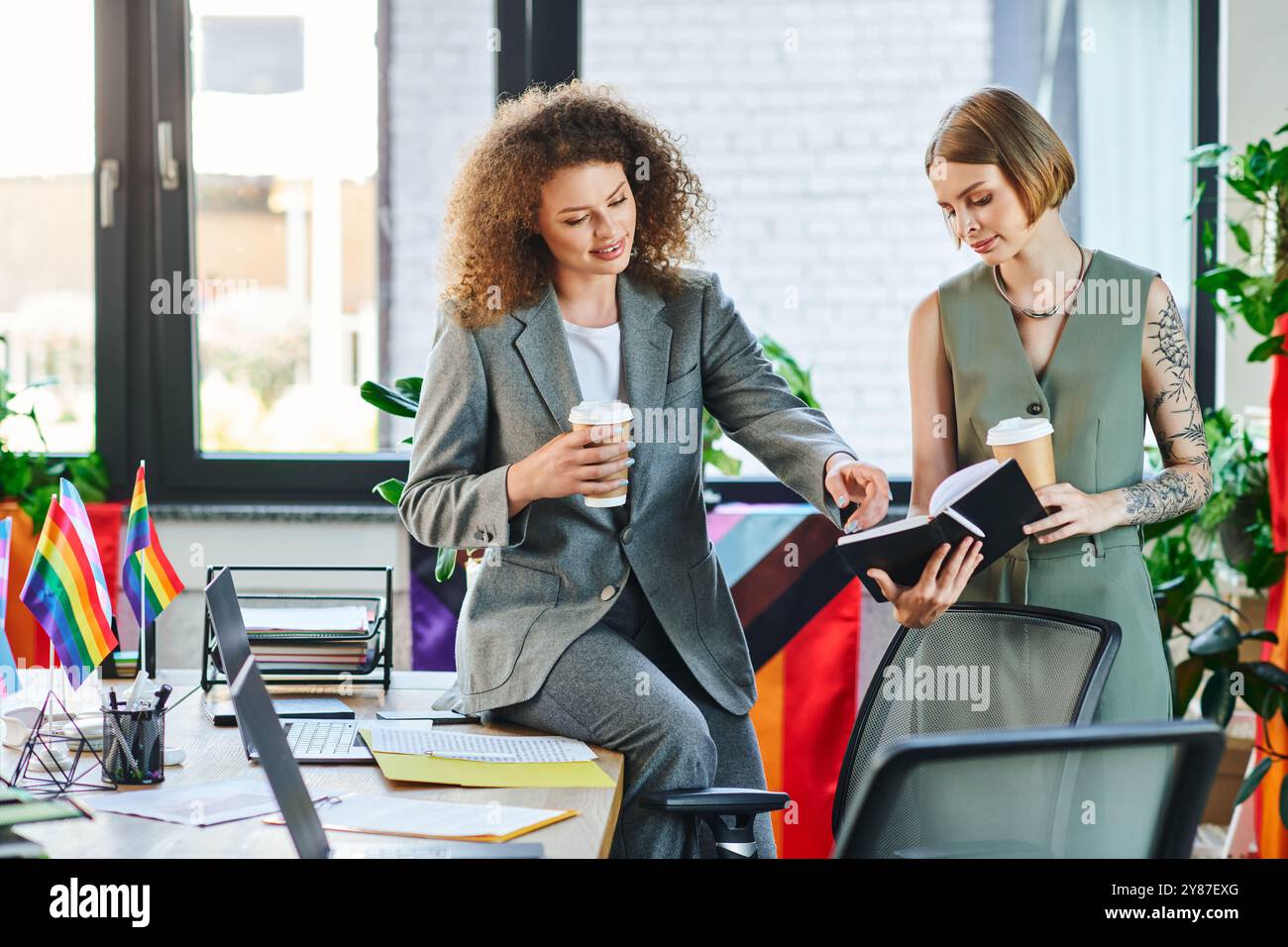 Two colleagues engage in a discussion over a notebook, surrounded by ...