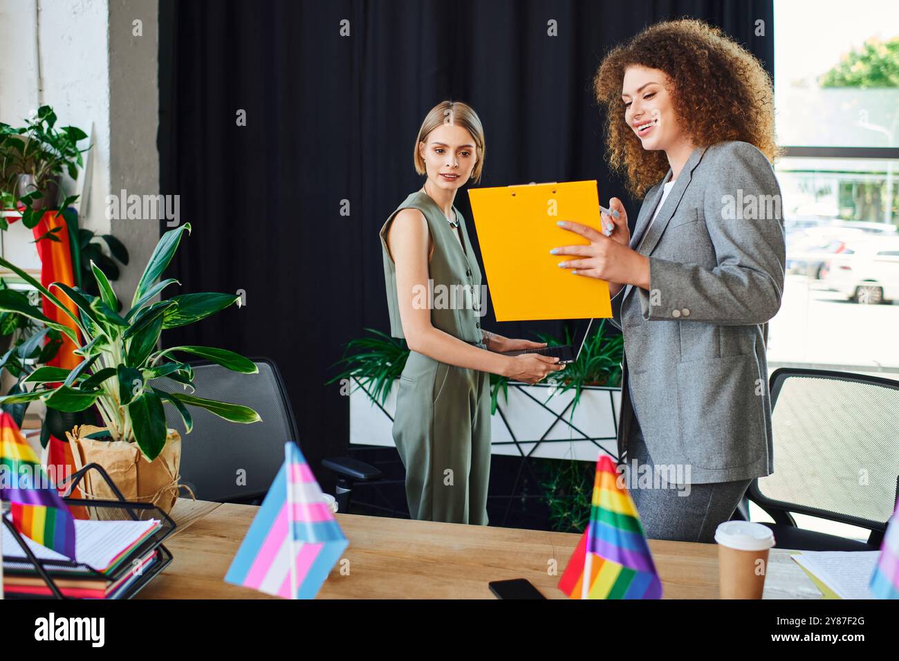 Two coworkers happily engage in a collaborative moment, sharing ideas ...