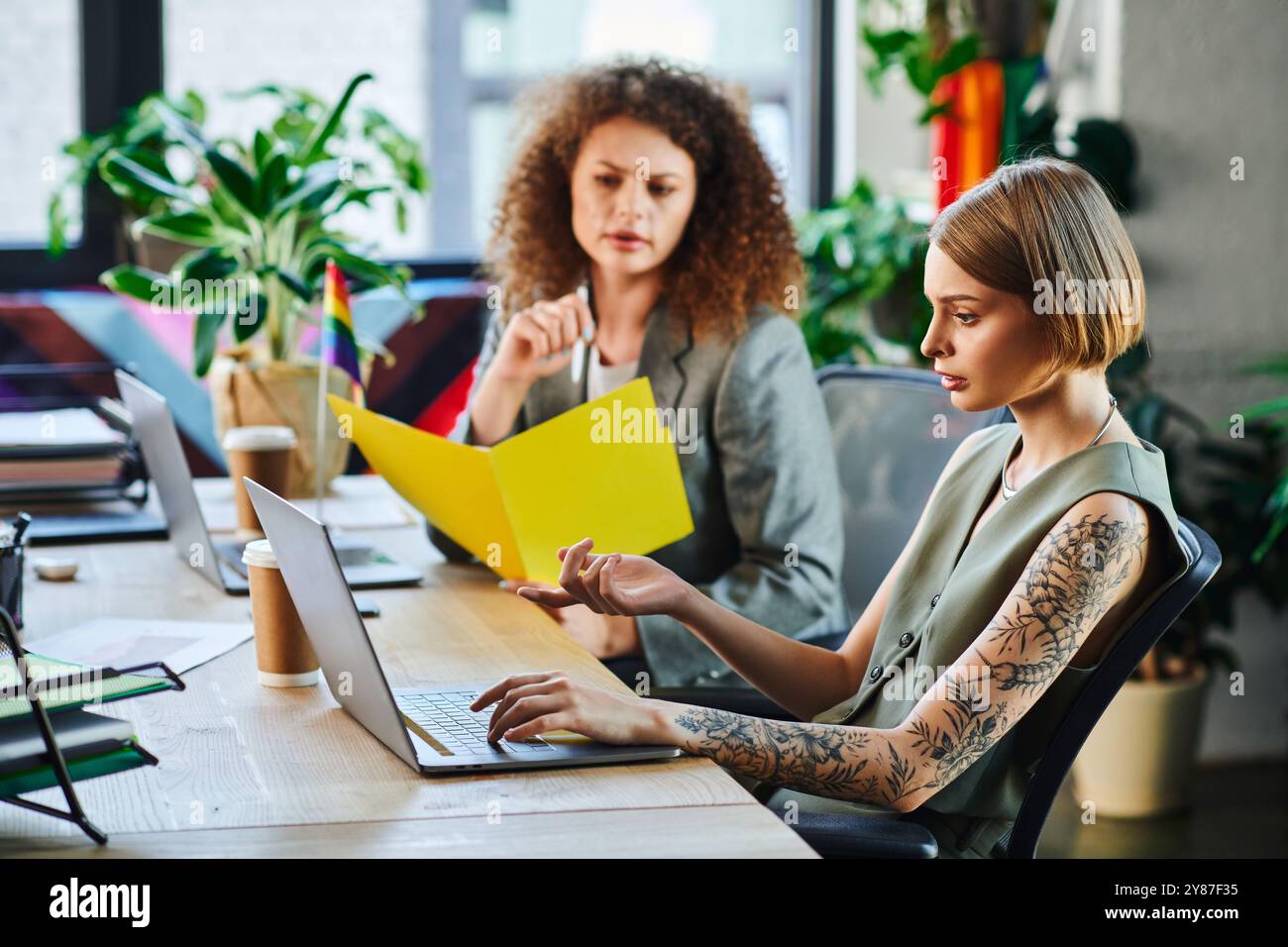 Two coworkers share ideas at a colorful office workspace, celebrating ...