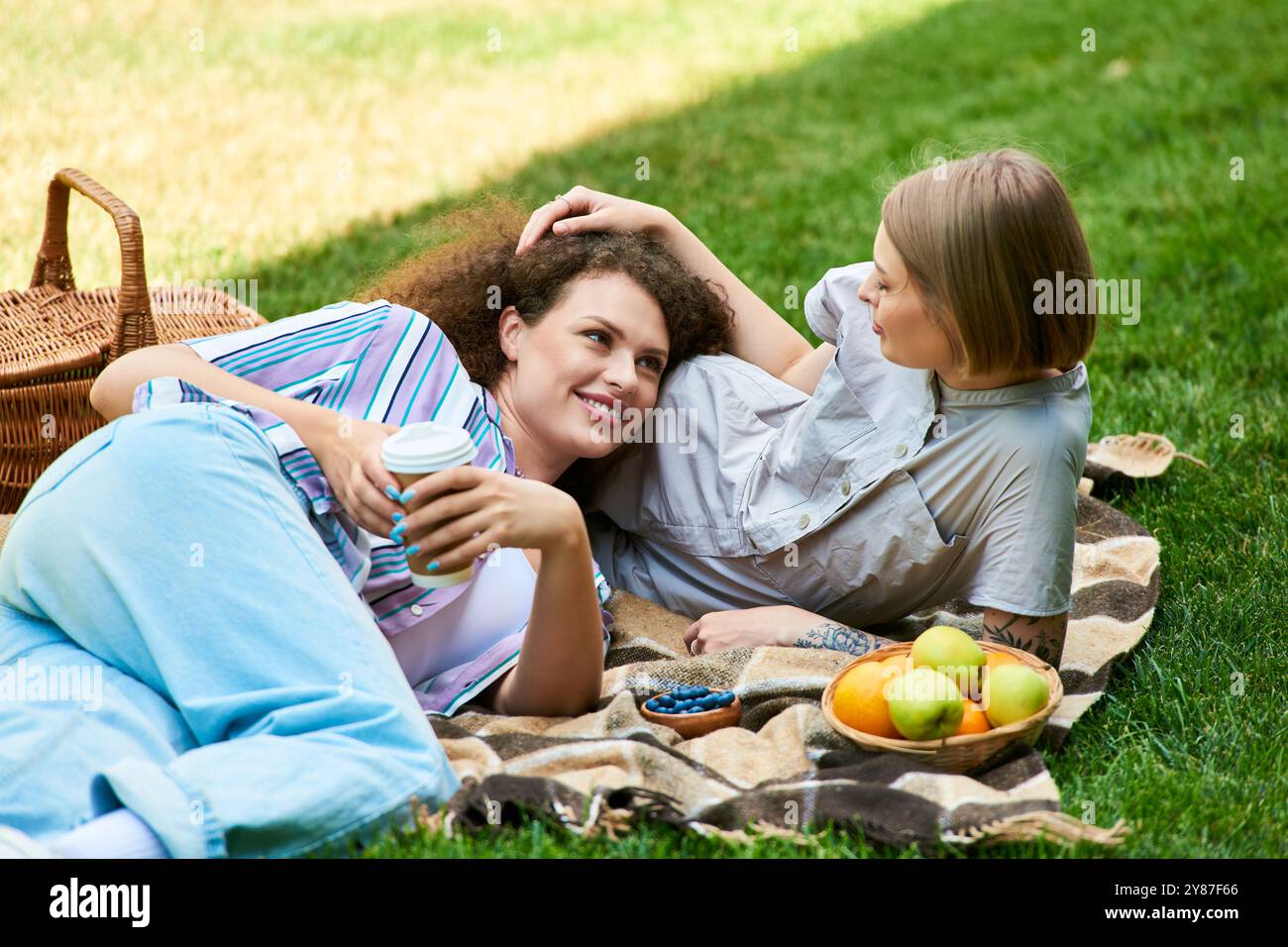 Two friends relax on a blanket, enjoying each others company and a ...