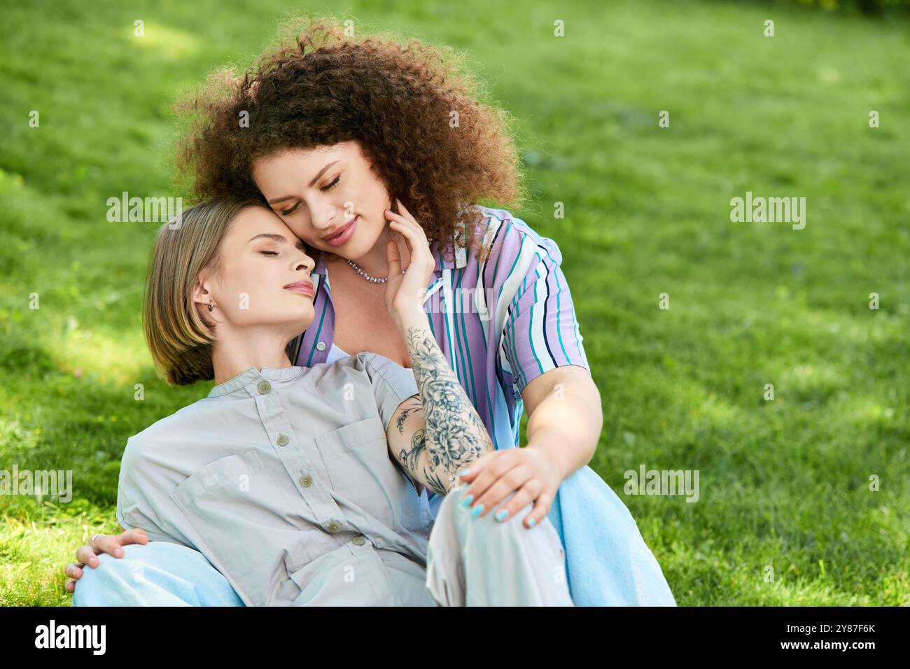 Two friends enjoy each other, laughing and relaxing on lush grass under ...