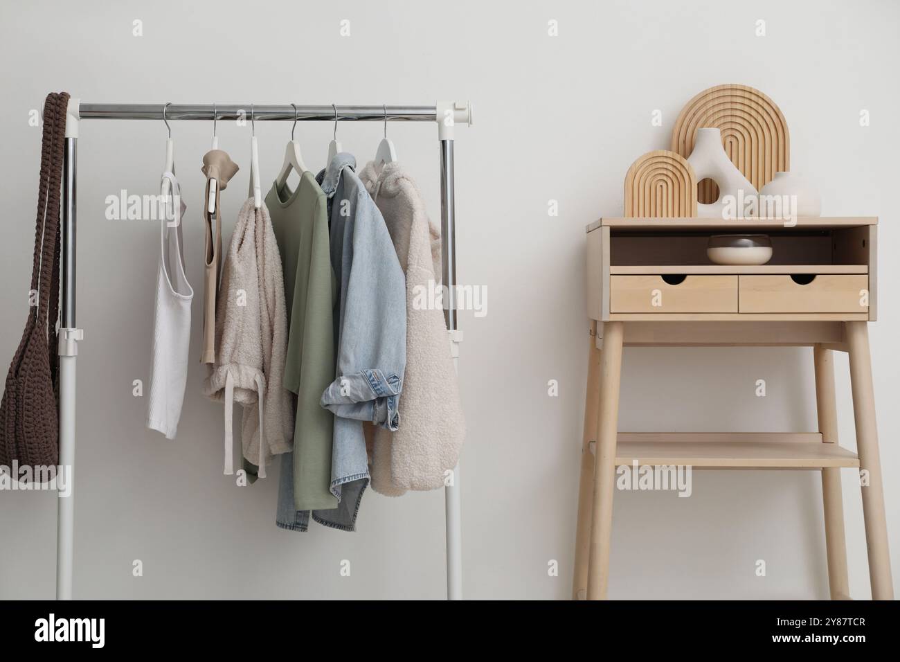 Rack with clothes and standing desk near white wall Stock Photo - Alamy