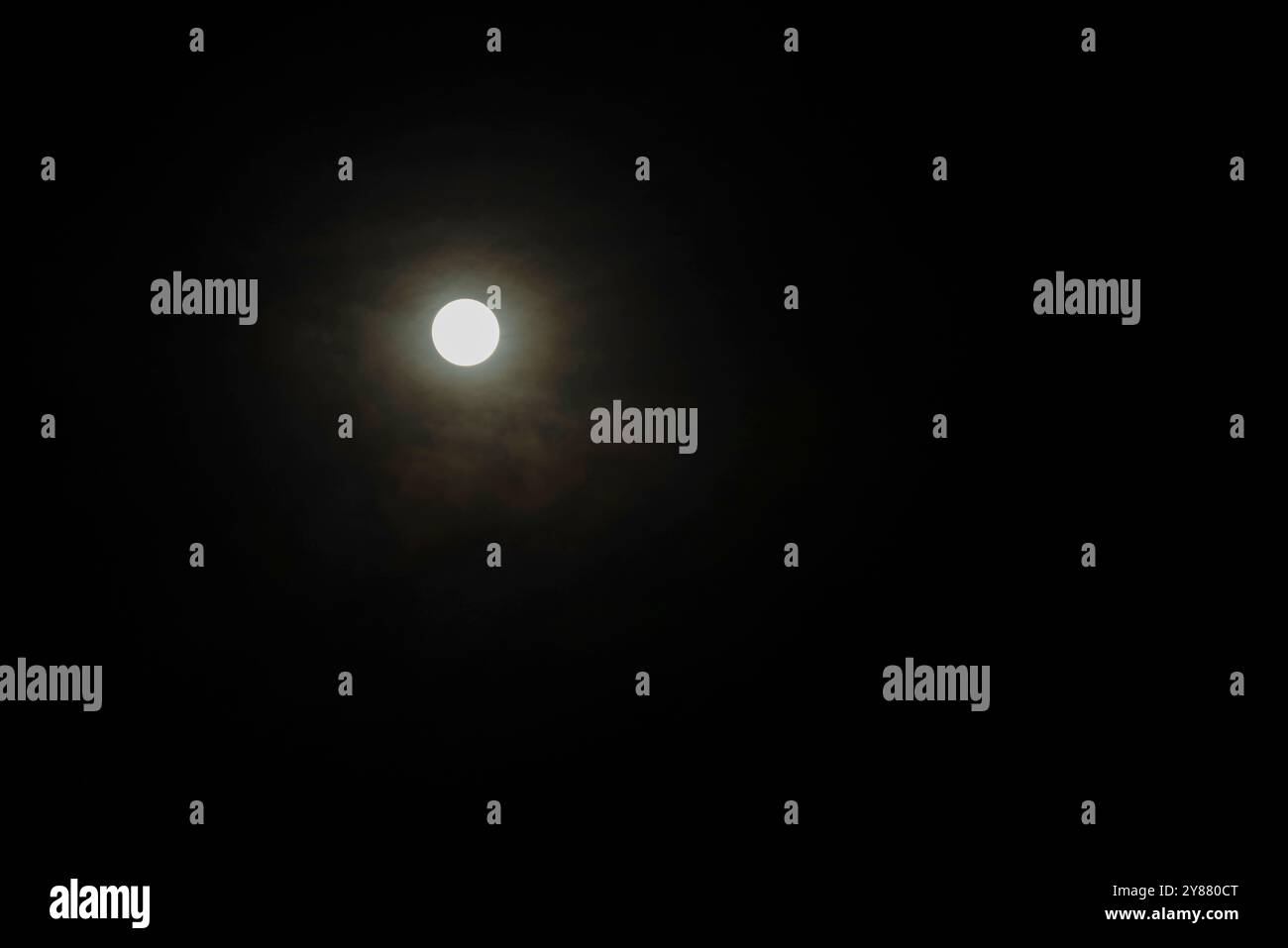 Full moon glowing in a dark night sky with a subtle cloud haze ...