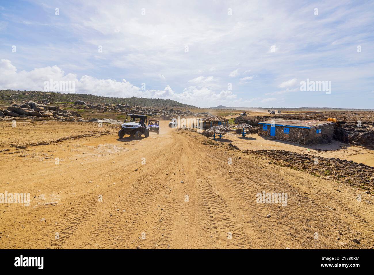 Dirt road with off-road vehicles driving through rugged desert ...