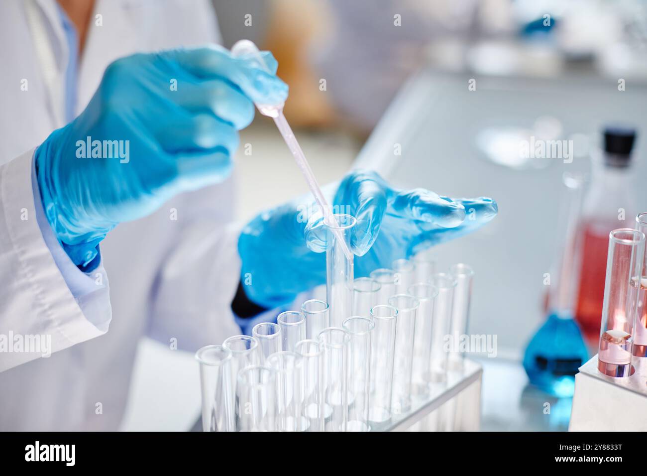 Close up on gloved hands of unrecognizable lab worker dripping liquid ...
