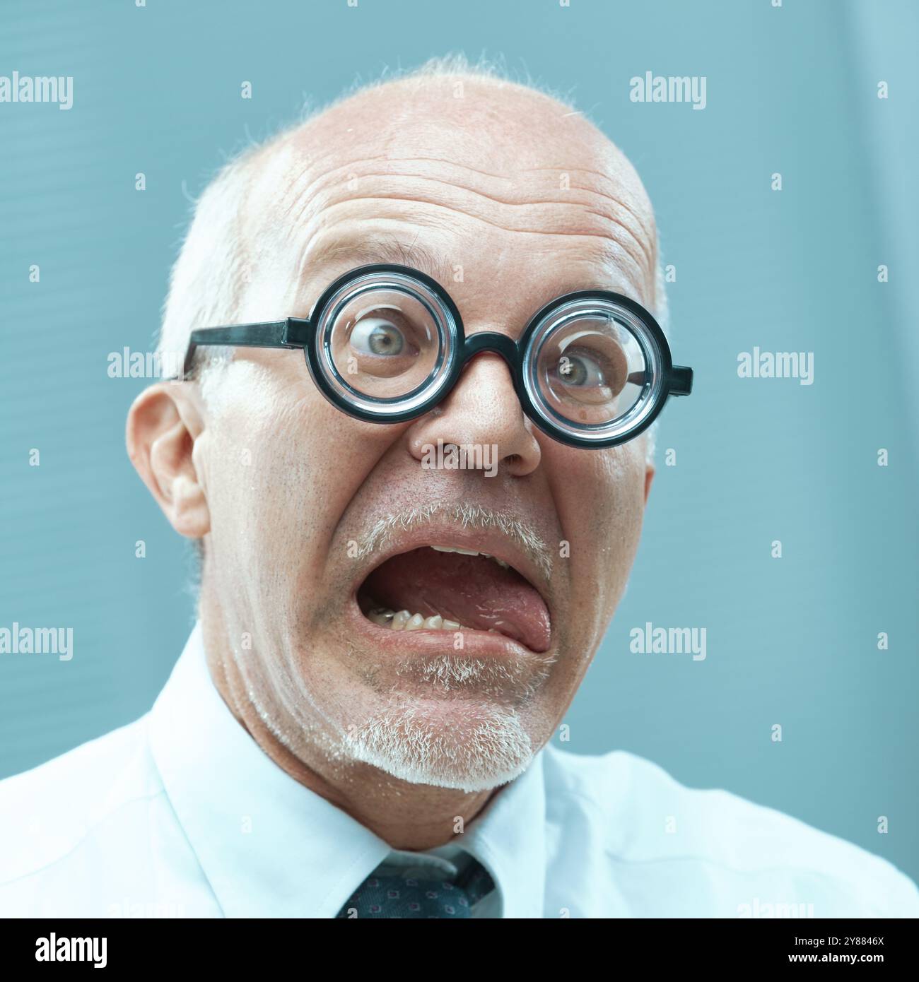 Mature businessman is making a silly face while wearing thick round ...