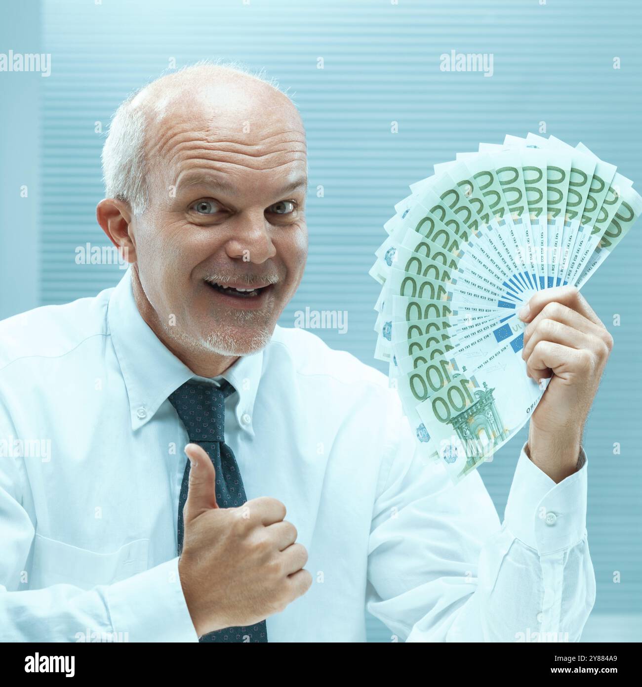 Senior businessman holding a fan of euro banknotes and showing thumbs ...