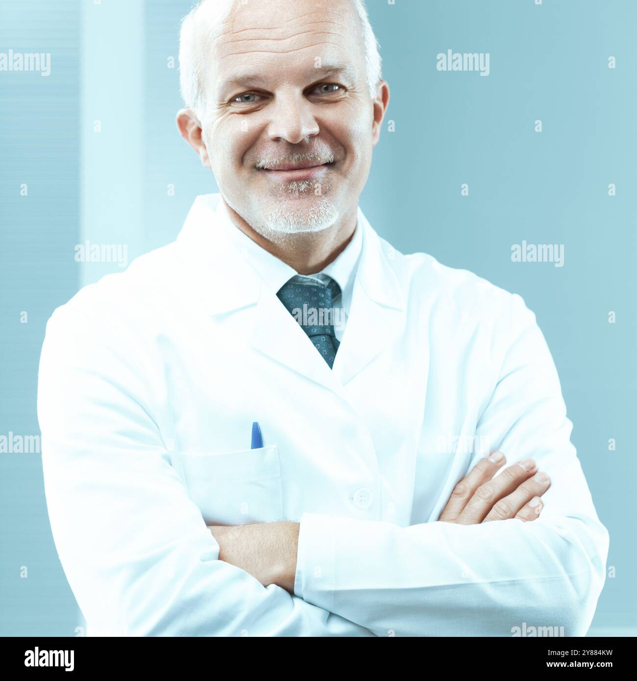 Mature doctor is standing in a hospital setting, wearing a white coat ...
