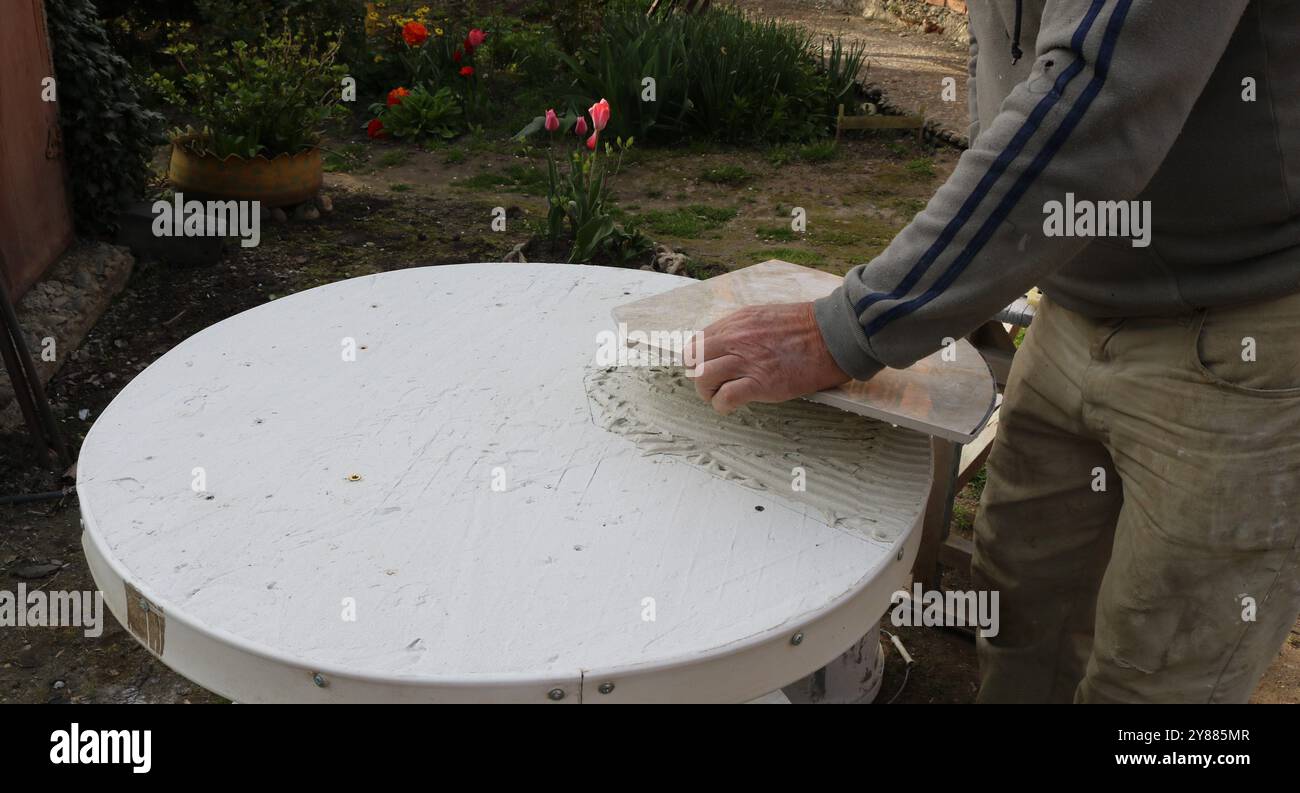 A craftsman places a piece of tile cut from a template onto a round ...