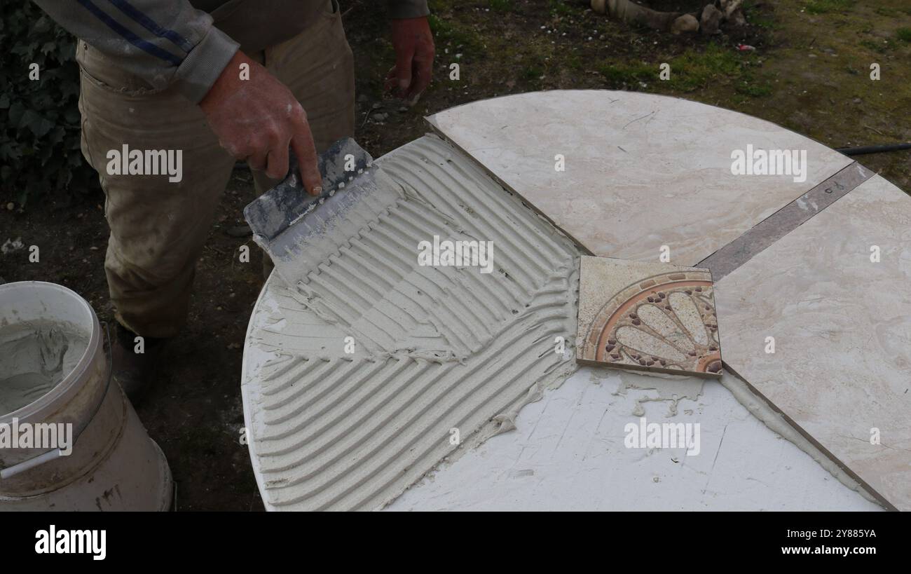 smoothing the solution applied for tiling the table surface with a ...