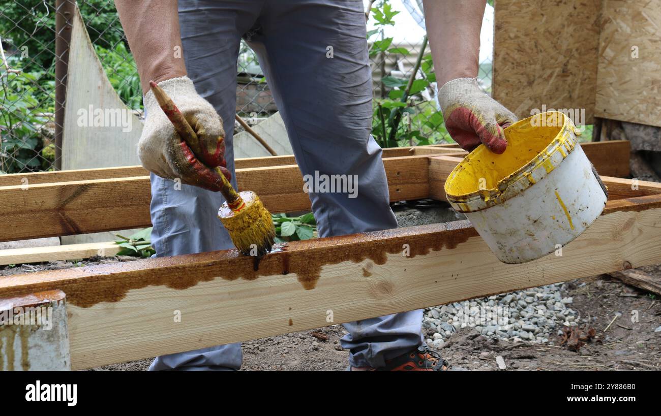 A construction worker in gray work clothes and gloves is making repairs ...