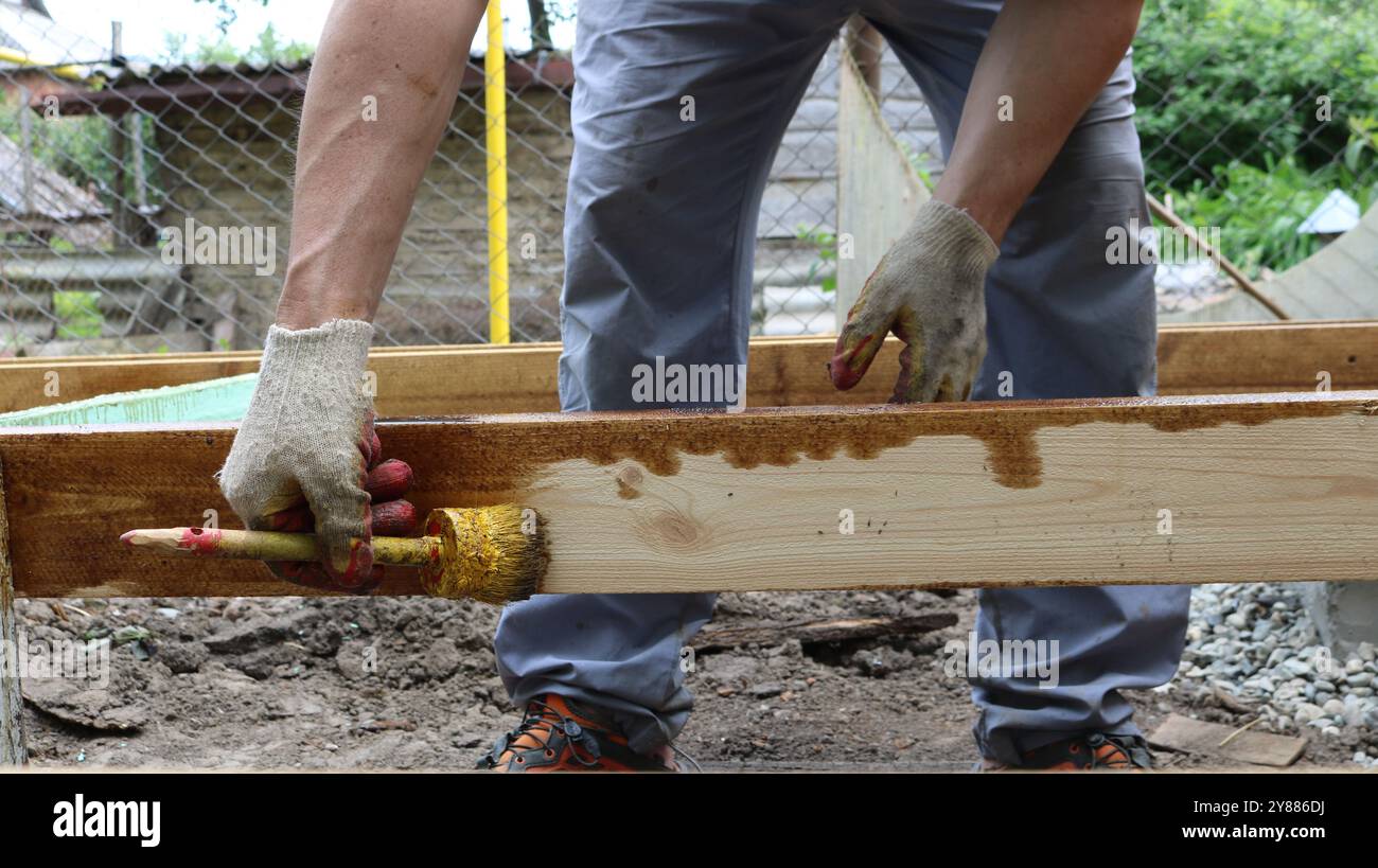 In the backyard a construction man in gray work pants and work gloves ...