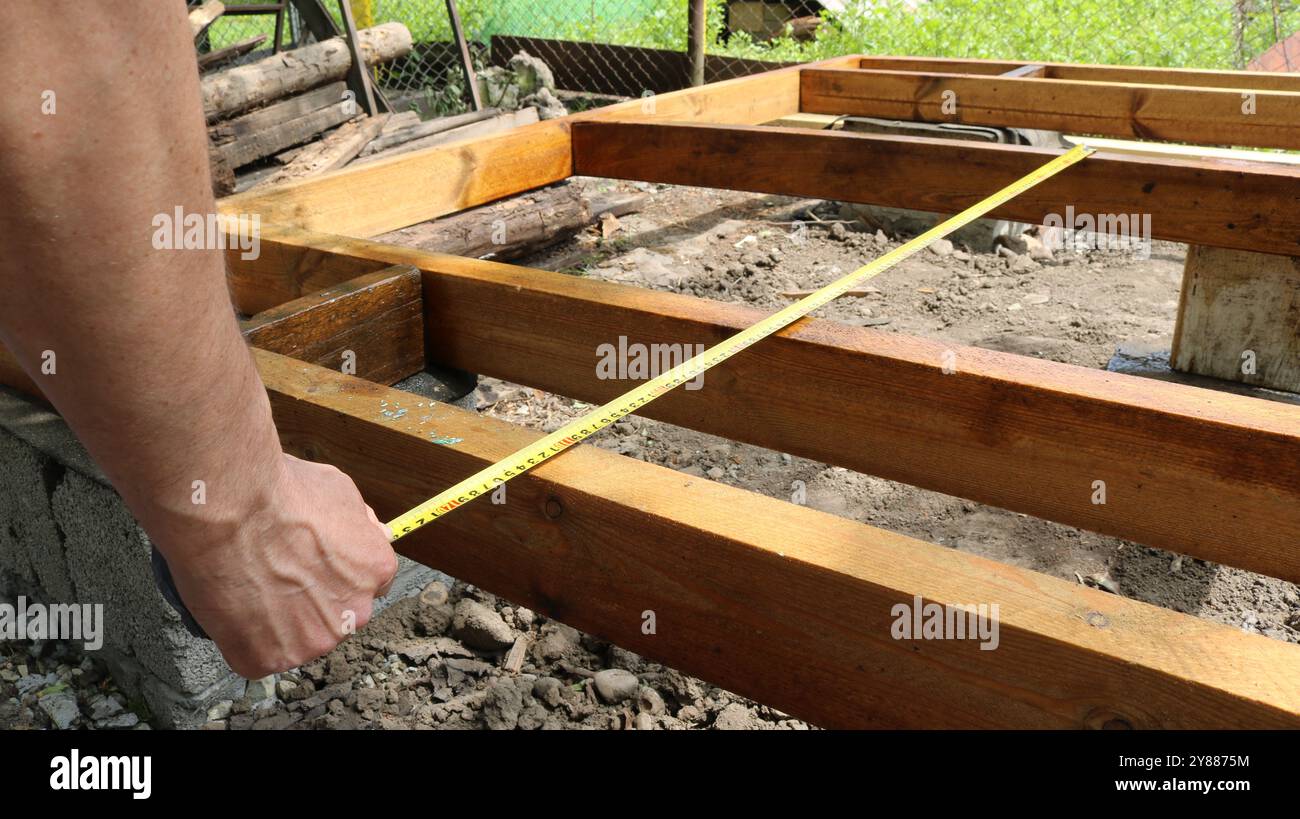 hands of a builder with a measuring tape measuring the distance between ...