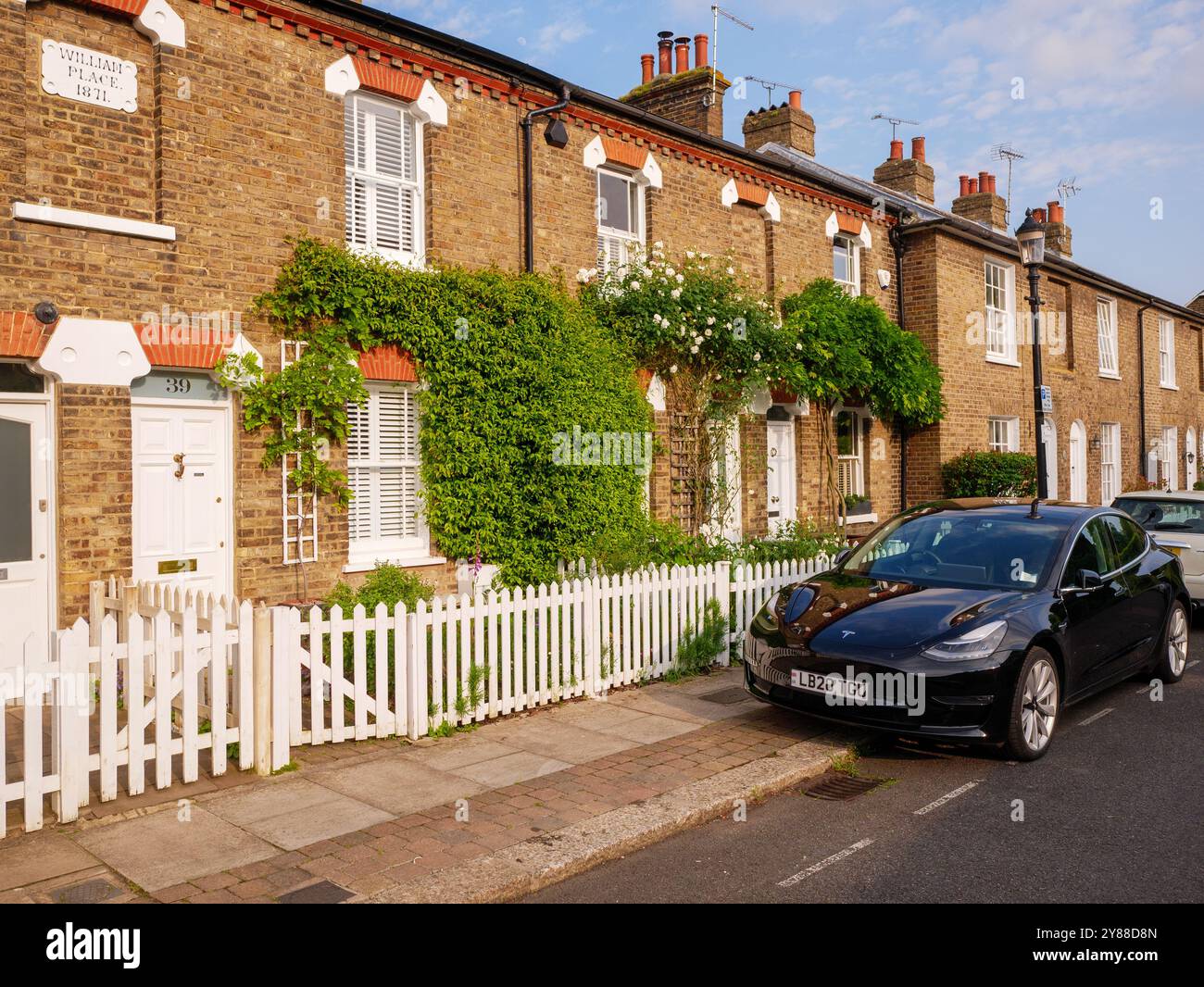 Tesla electric car parked on the street outside a row of Victorian ...