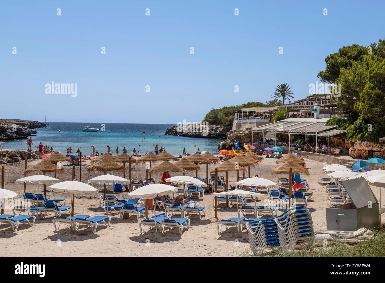 People enjoy the beautiful beach of the seaside resort of Cala Blanca ...