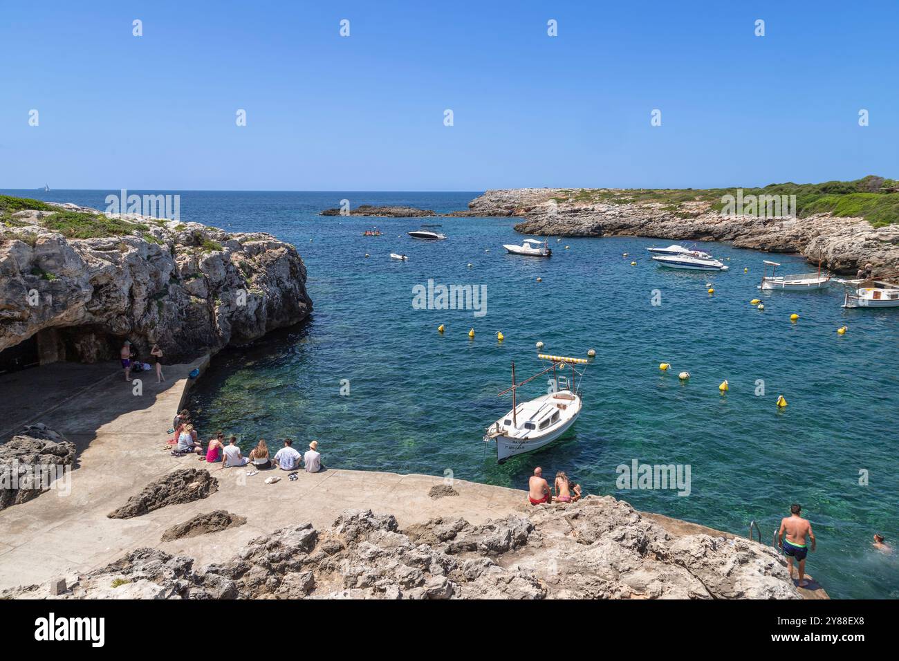 People sit and swim at the small harbor of the coastal village of ...