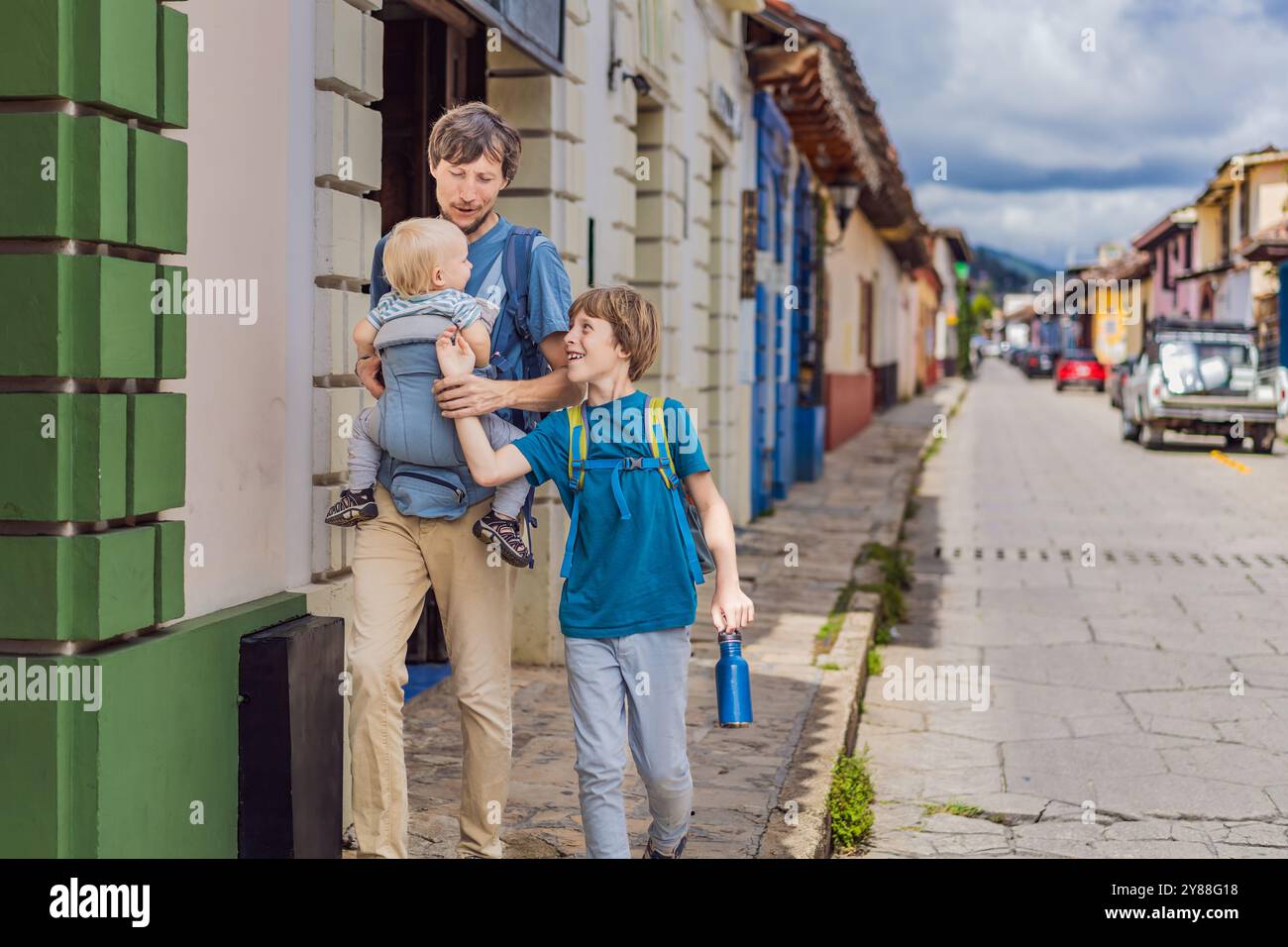 Father and and his two sons, a teenager and a baby tourists walks ...