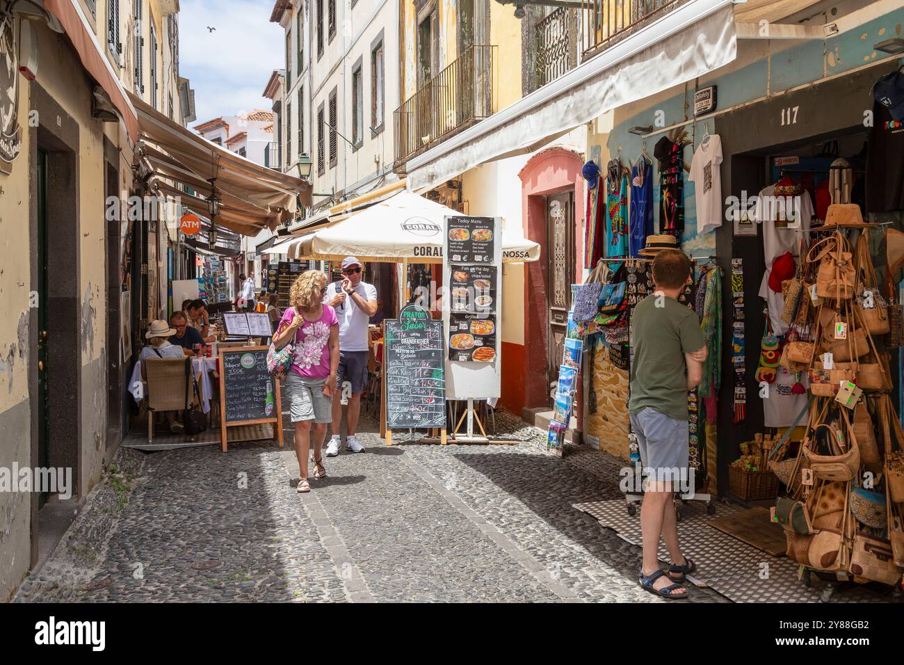 People walk through the cozy Santa Maria street with shops, bars and ...