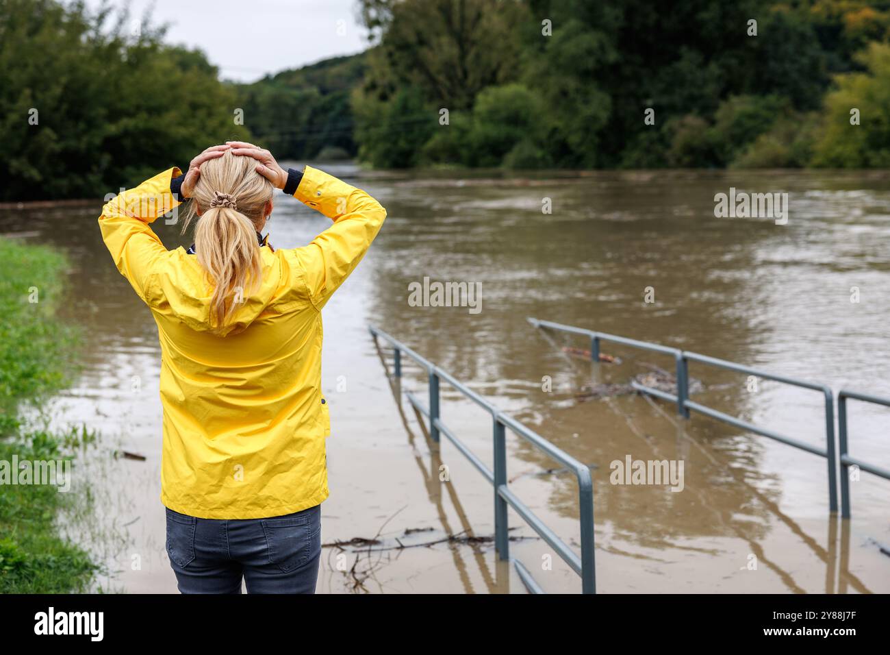 Worried woman looking at flooded river. Impact of climate change and ...
