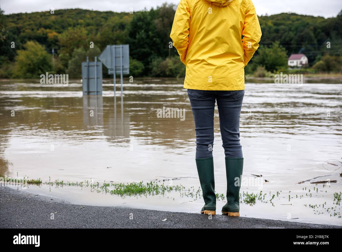 Flood after intense rain. Worried woman looking at flooded river ...