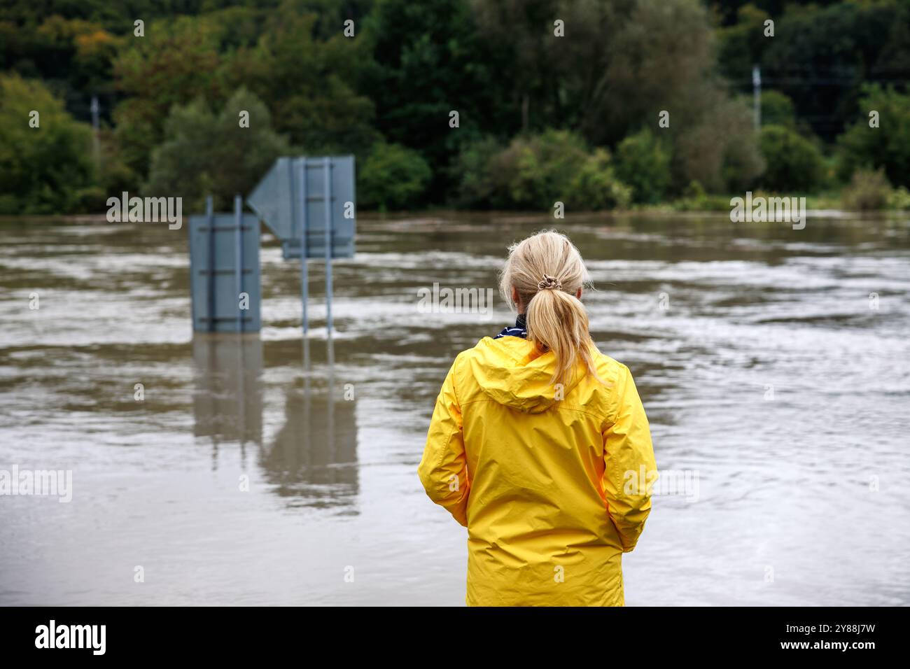 Flooded river. Worried woman looking at overflowing water during flood ...