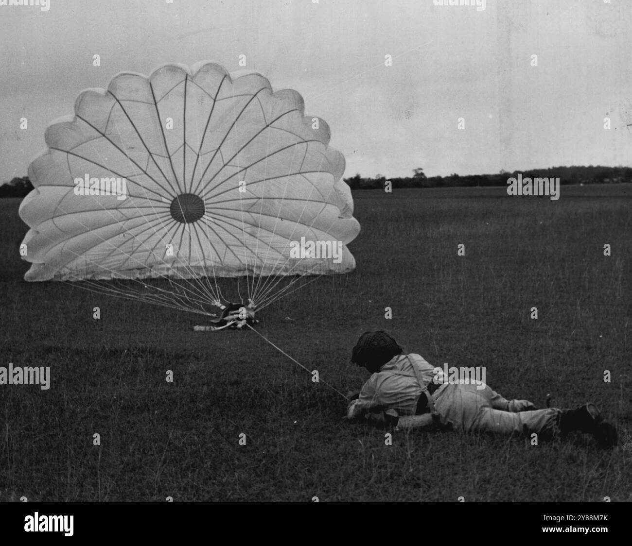Parachute billows before collapsing, as a Paratrooper lands safely on ...