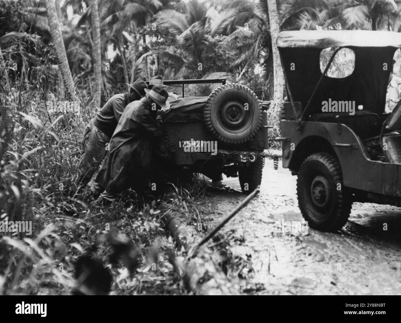 War correspondents' Jeep gets bogged down on a Dutch New Guinea road ...