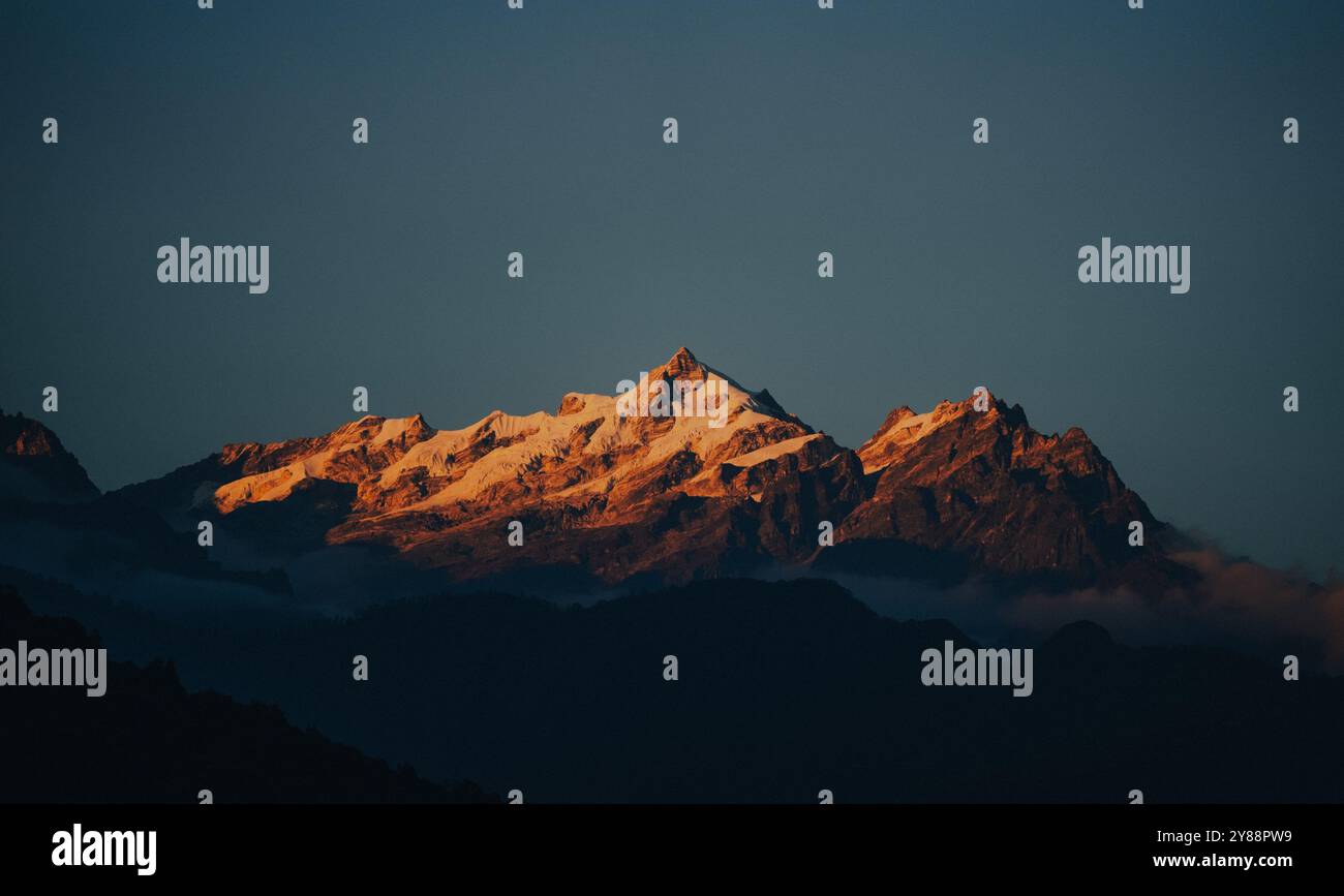 A breathtaking mountain range illuminated by golden sunlight. Snowy ...