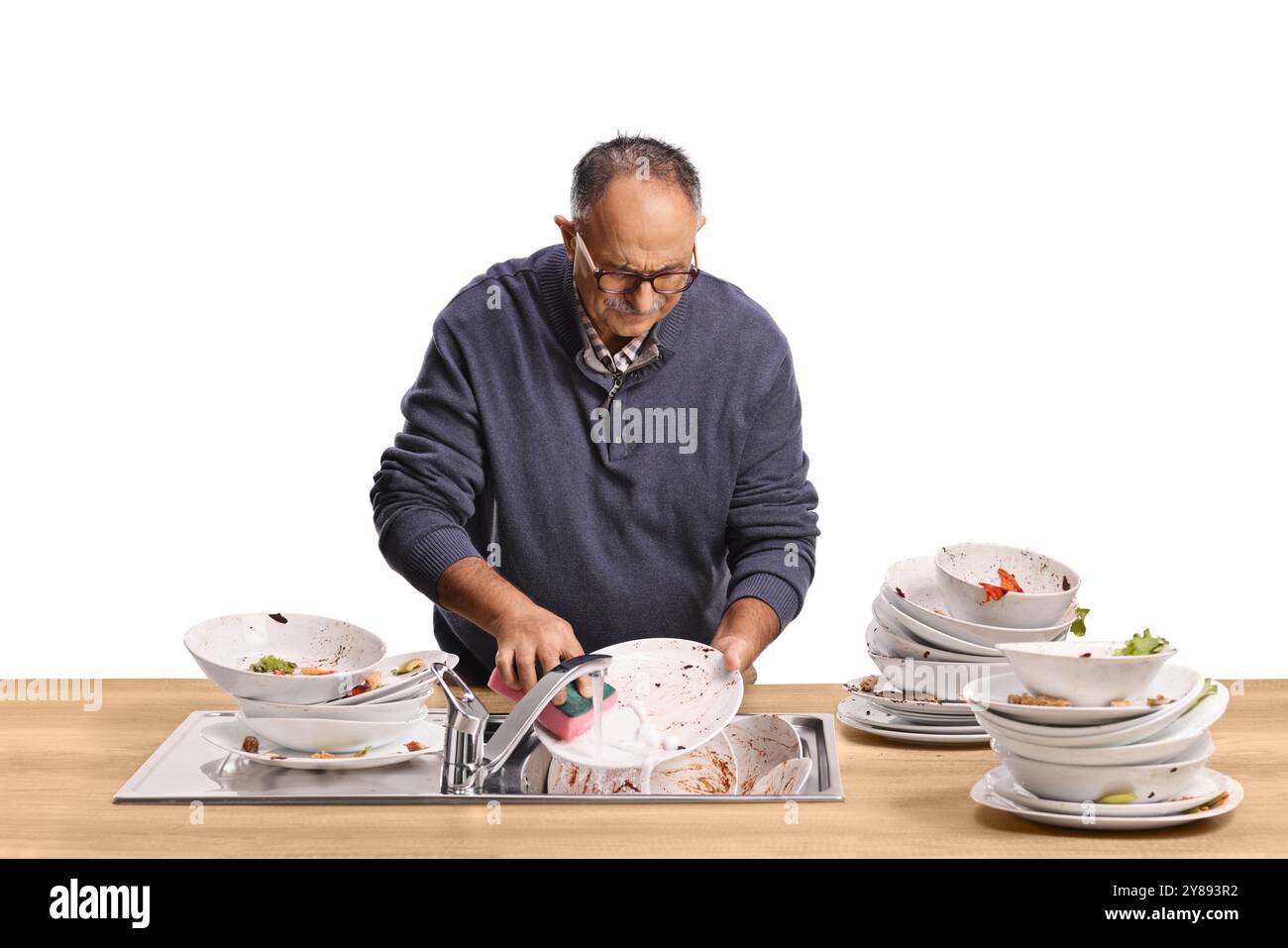 Mature man washing dirty dishes in a kitchen sink on a wooden counter ...