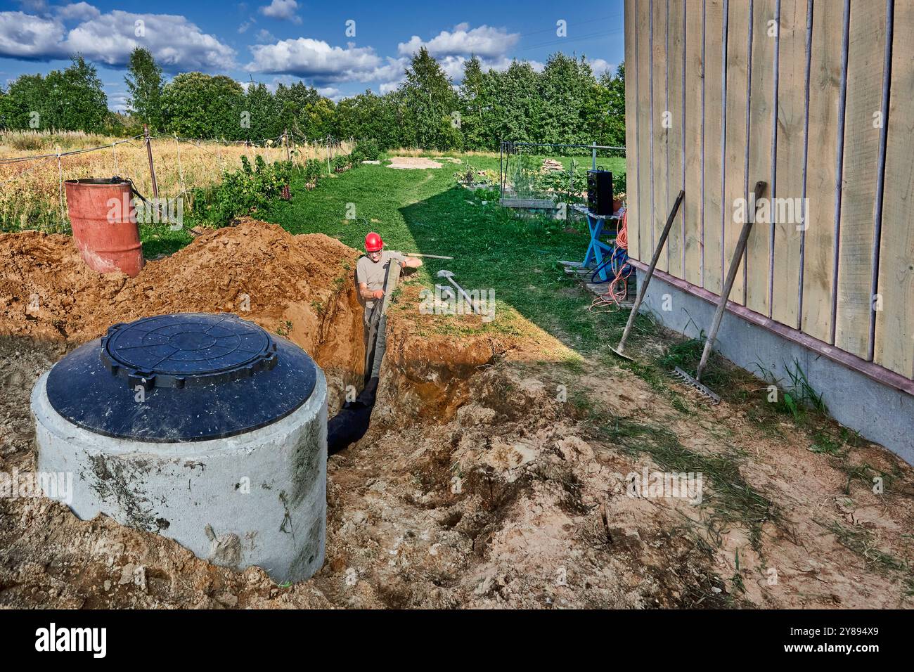 Plumber connects drainage pipe to septic tank outlet pipe to carry ...